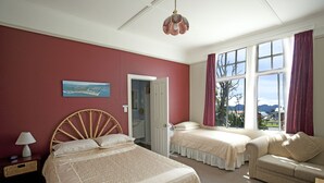 Quarto com uma cama grande, duas mesas de cabeceira, uma cadeira e uma janela com cortinas.