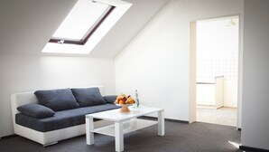 Uma sala de estar moderna com um sofá branco, uma mesa de centro com frutas e um claraboia.