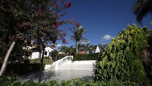 Um caminho que leva a um edifício com fachada branca e uma escadaria.