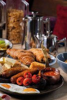 Prato de café da manhã com ovos, salsichas, tomates e torradas.