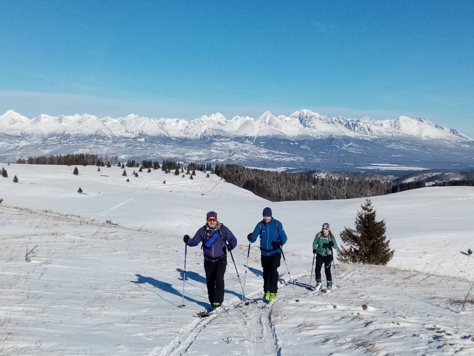 Paisagem nevada com três esquiadores.