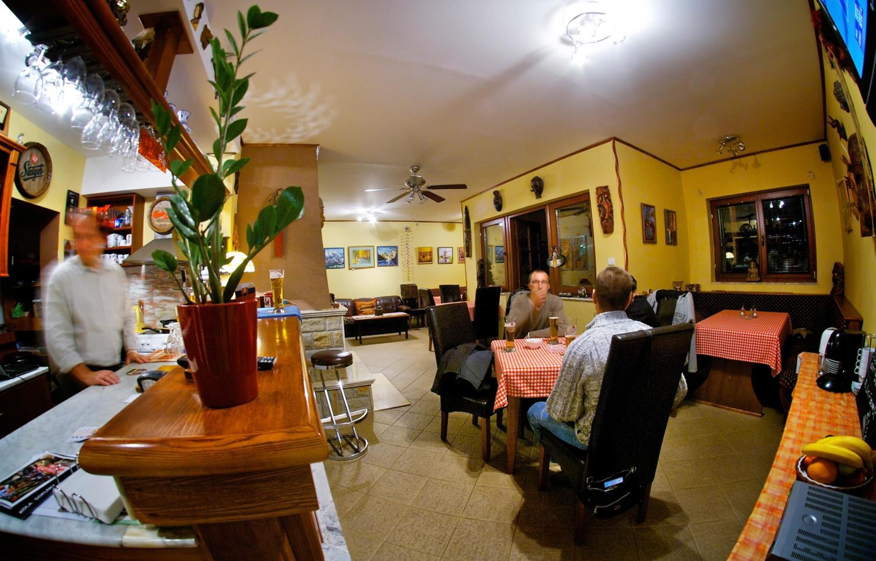 Um restaurante com área de bar, várias mesas e cadeiras.