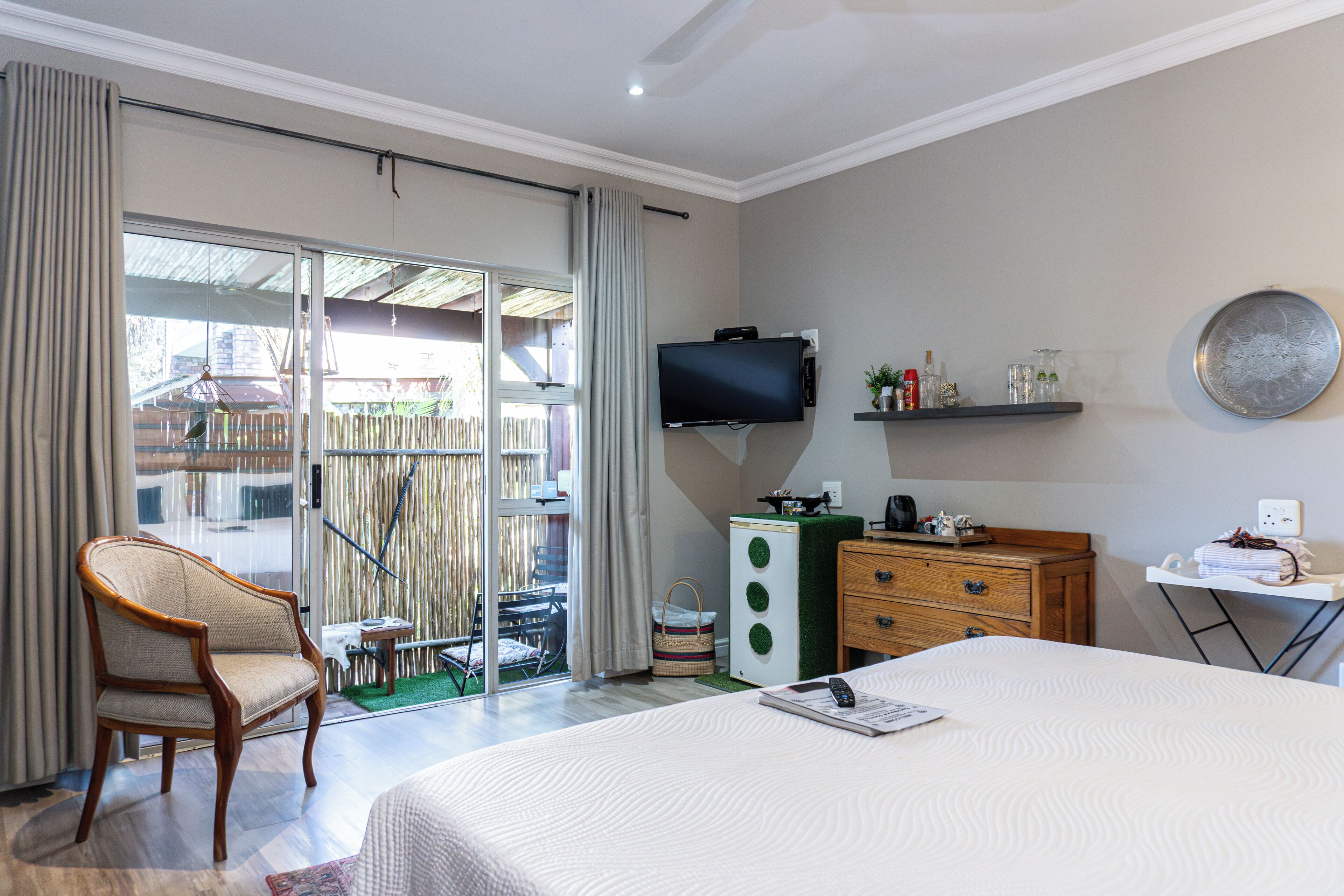 Quarto de hotel com cama, poltrona, televisão, escrivaninha e varanda com vista.