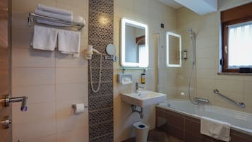 Casa de banho moderna com sanita, lavatório e banheira. Há toalhas numa barra e um espelho sobre o lavatório.