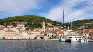 Uma cidade costeira com edifícios históricos, uma imponente torre do relógio e vários barcos atracados no porto.