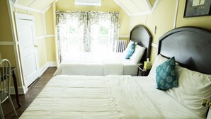 Quarto com duas camas, janela com cortinas florais e radiador.