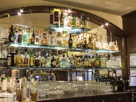 Uma área de bar com várias prateleiras de garrafas de bebidas e uma variedade de copos.