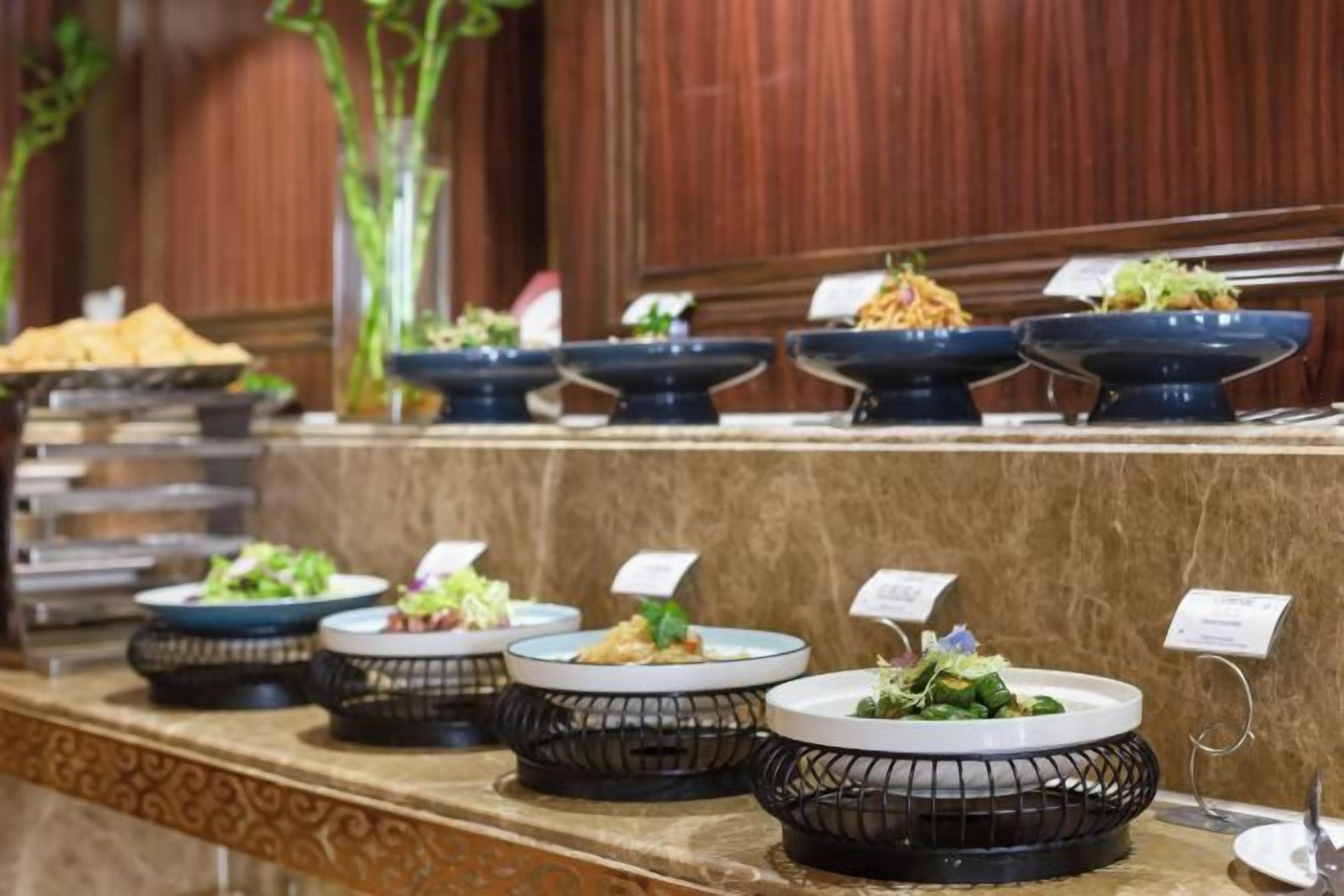 Disposição de buffet com diversos pratos e etiquetas.