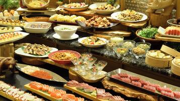 Buffet variado com diversos pratos, incluindo sushi, saladas e outros petiscos.