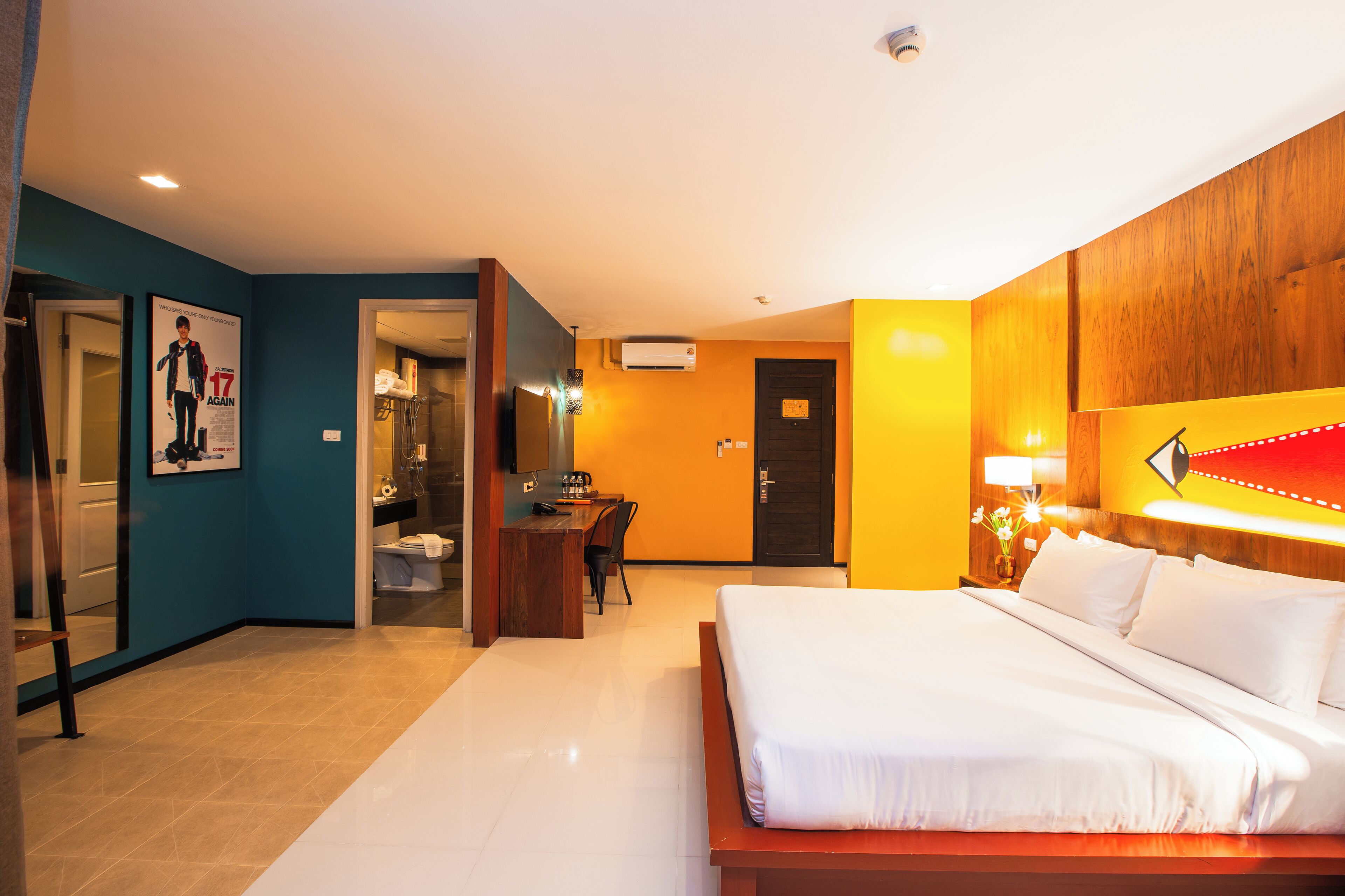 Quarto de hotel com uma cama grande, uma escrivaninha e um banheiro.