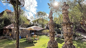 Um jardim de esculturas em pedra com um muro de pedra e uma árvore em primeiro plano.