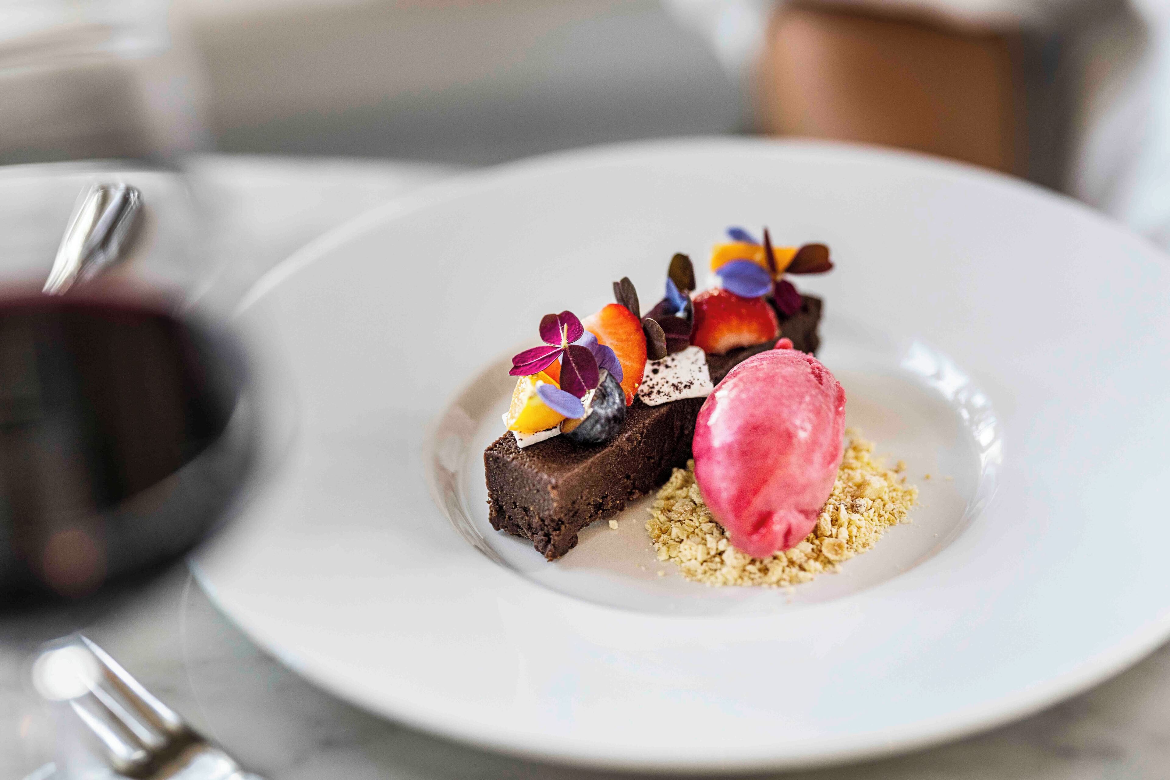Um prato de sobremesa com um brownie de chocolate, fruta e sorvete.