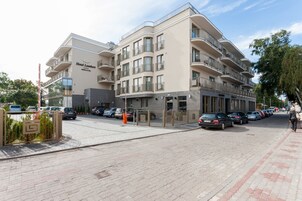 Um hotel com vários andares, varandas, entrada com portão e estacionamento.