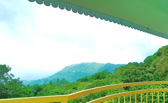 Uma varanda com vista para colinas verdejantes e uma montanha ao longe.