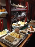 Buffet com diversos alimentos, incluindo pão, doces e frutas.