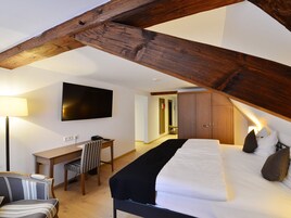 Quarto com cama, escrivaninha, cadeira, televisão e guarda-roupa.