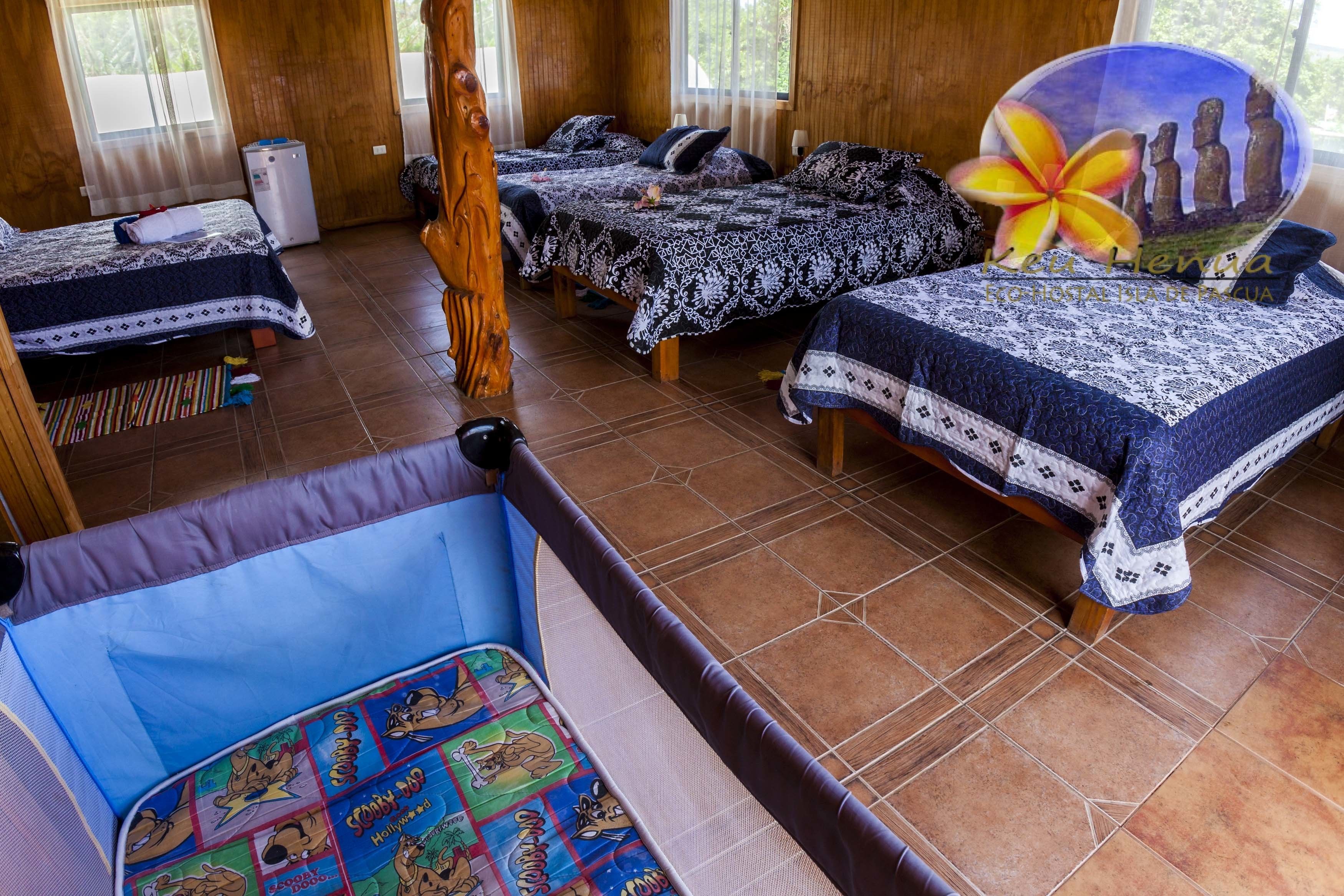 Quarto com quatro camas, piso de madeira e vista para o exterior.