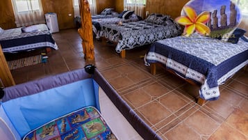 Quarto com quatro camas, piso de madeira e vista para o exterior.