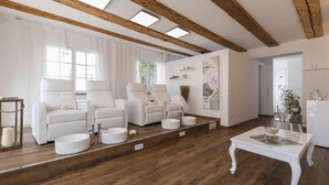 Uma sala de estar espaçosa com teto de madeira, sofás brancos, uma mesa de centro e uma janela grande com cortinas.