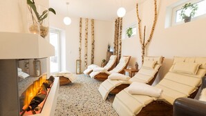 Um espaço de spa com lareira, cadeiras de descanso e chão com padrão de pedras.