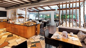 Espaço de café da manhã com buffet, assentos e vista para o exterior.