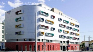 Um edifício com várias andares, fachada branca e varandas coloridas.