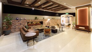 Um hall com parede de tijolos, lareira, assentos de couro e um balcão de recepção.