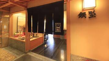 Decoração tradicional japonesa com teto de madeira, cortina preta e uma placa com caracteres japoneses.
