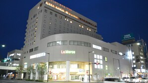 Um hotel de vários andares com uma placa grande 'La Merce', apresentando um design arquitetônico moderno com janelas amplas e fachada curva.