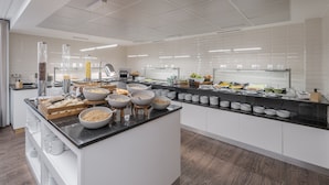 Uma cozinha moderna com ilha central, diversos pontos de preparo de alimentos e um layout limpo e organizado.