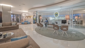 Um hall de hotel moderno com uma mesa de recepção, área de estar e uma grande janela.