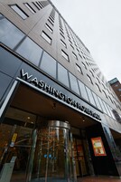 Exterior do Washington Hotel Plaza, com fachada de vidro moderna e entrada imponente.