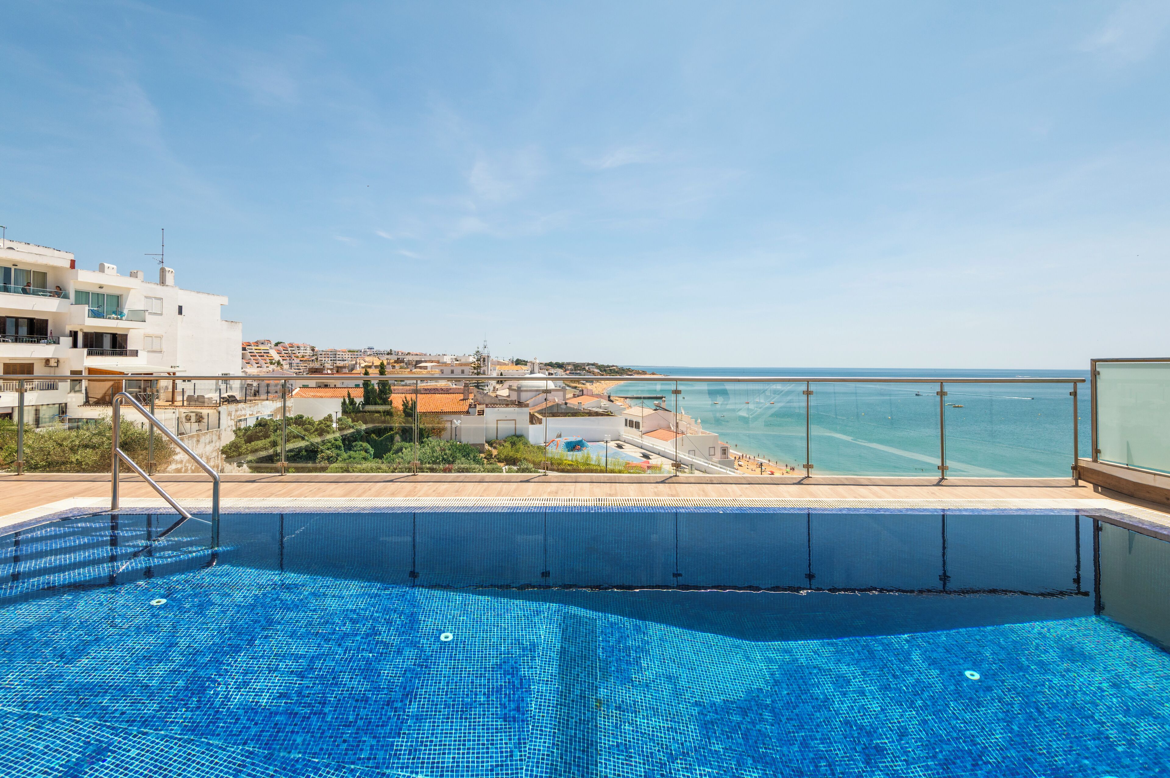 Piscina no terraço com vista para o mar e edifícios.