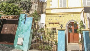 Um edifício com fachada amarela, porta de madeira e um portão.