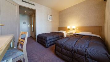 Quarto de hotel com duas camas, uma mesa e uma cadeira.