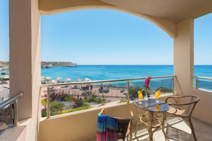 Varanda com vista para o mar, uma mesa com bebidas e uma cadeira.