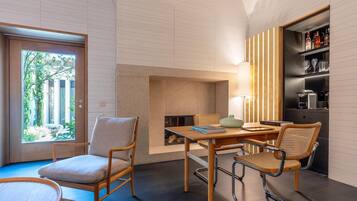 Um interior moderno com área de refeições, cadeiras, mesa, lareira e cozinha com prateleiras.