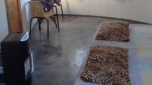 Quarto com cama, escrivaninha e cadeira. Há uma janela com cortinas, uma porta e um radiador.