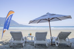 Na praia, espreguiçadeiras, guarda-sóis, toalhas de praia