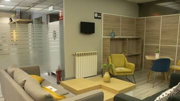 Uma sala de estar moderna com um sofá, poltronas, uma mesa de centro e uma TV fixada na parede.