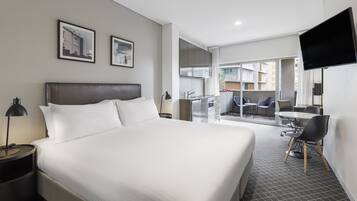 Quarto de hotel moderno com uma cama grande, uma escrivaninha e uma televisão de tela plana.