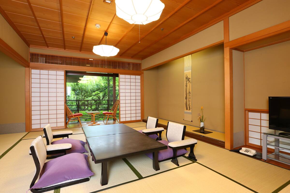 Um quarto japonês tradicional com tatames, uma mesa baixa e assentos.