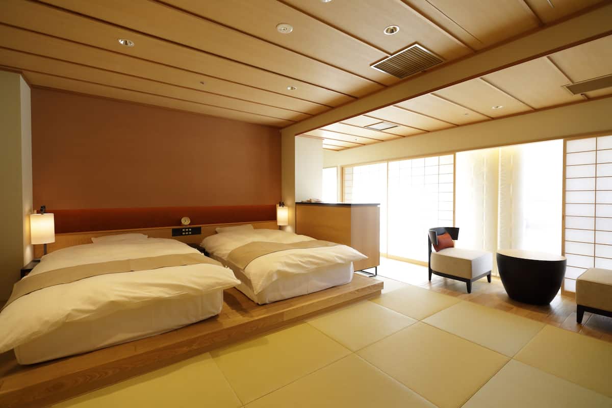 Quarto de hotel com uma cama grande, uma cadeira e uma pequena mesa.