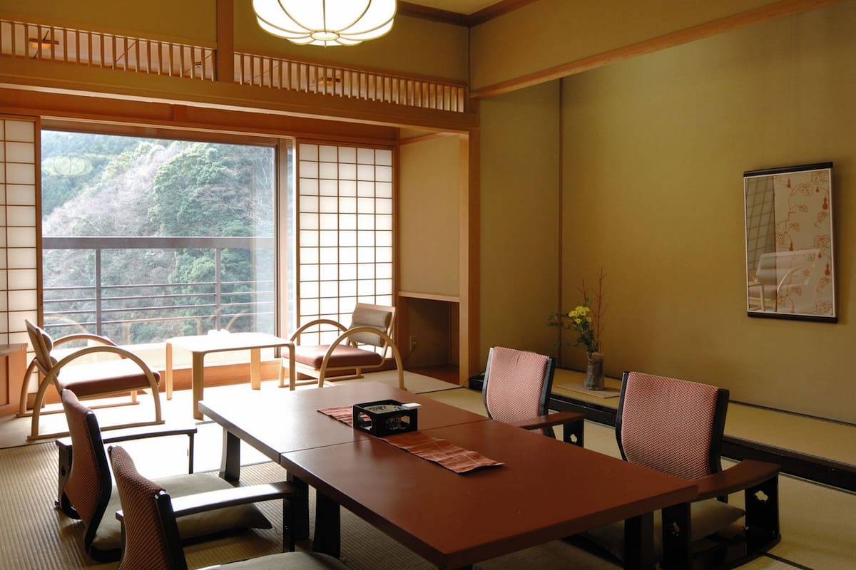 Uma sala de reuniões tradicional japonesa com tatames, mesinhas baixas e cadeiras de madeira.