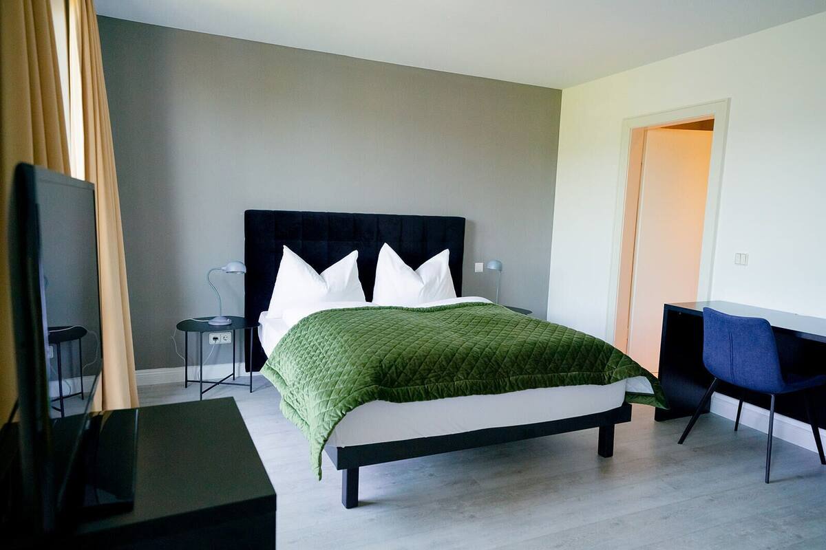 Quarto de hotel moderno com cama, escrivaninha e cadeira.