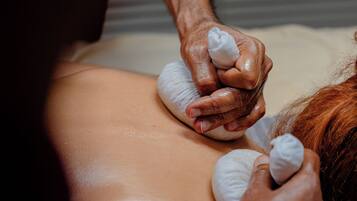 Primeiro plano de uma massagem, com mãos aplicando creme nas costas de uma pessoa.
