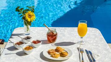 Uma mesa com toalha branca, um prato de comida, um copo de suco de laranja e um vaso com um girassol.