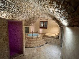 Área de spa com teto de pedra, hidromassagem e espaço para relaxamento.