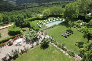Vista aérea de um jardim bem cuidado, com piscina, espreguiçadeiras e área de terraço.