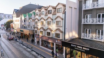 Um edifício com vários andares que combina espaços residenciais e comerciais, incluindo uma loja no andar térreo.